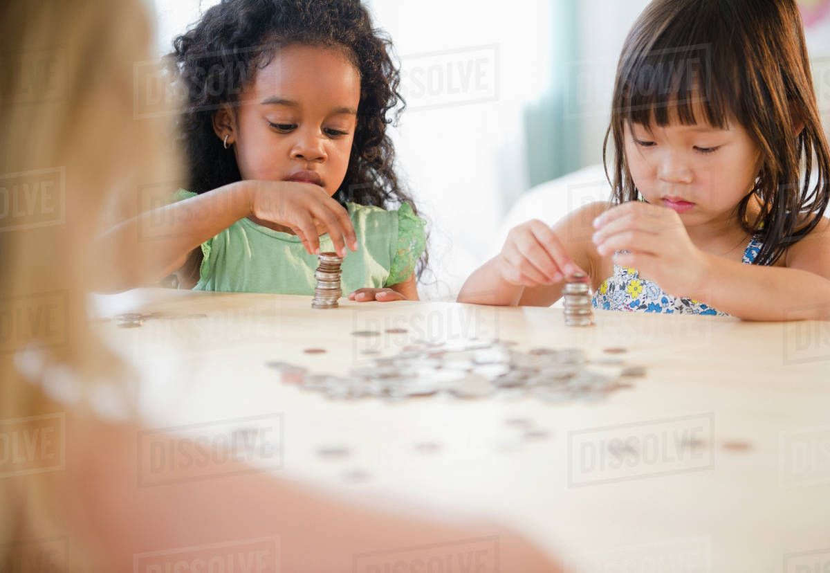 Girls stacking coins together - Royalty-free Stock Photo | Dissolve