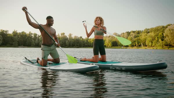 African american couple paddle boarding together on lake - Stock Video ...