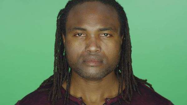 Close-up of a man with dreads looking serious, on a green screen studio ...