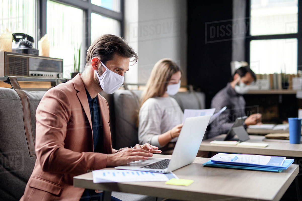 Business people with face masks working indoors in office, back to work ...