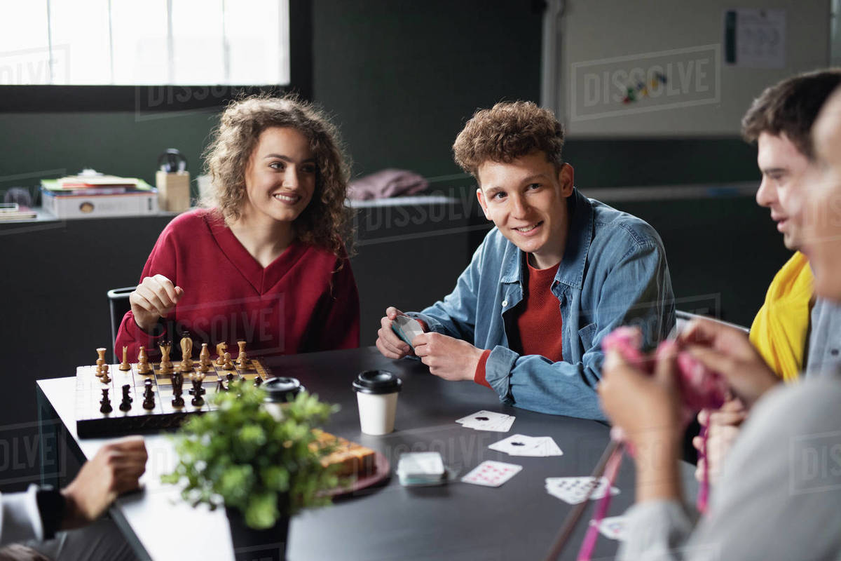Group of happy people playing cards and board games in community center ...