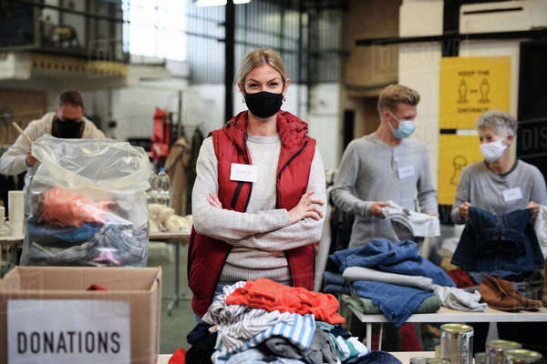 Group of volunteers working with food and clothes in community charity ...