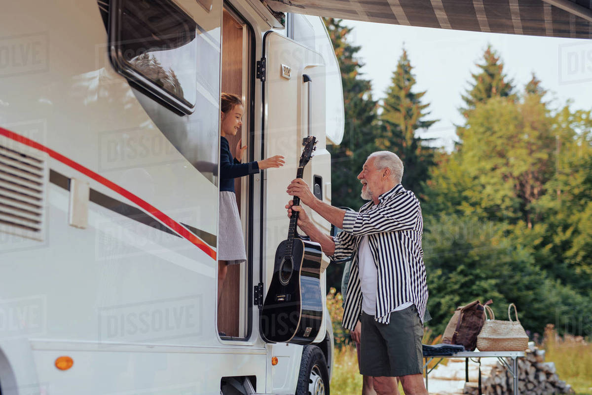 Happy multi-generation family unpacking and talking by car, caravan ...