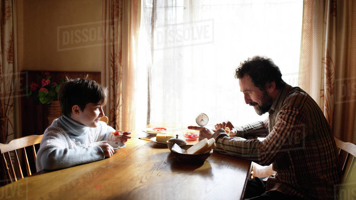 A portrait of poor small girl with father eating indoors at home ...