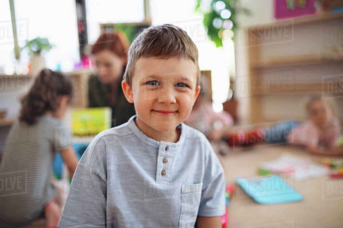 A portrait of small nursery school boy indoors in classroom, looking at ...