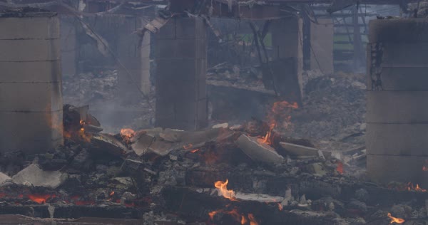 Smoldering rubble around the foundation pillars of a house gutted by ...