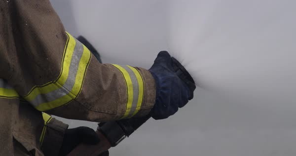Firefighter's hands adjusting the nozzle of a spraying fire hose - HD ...