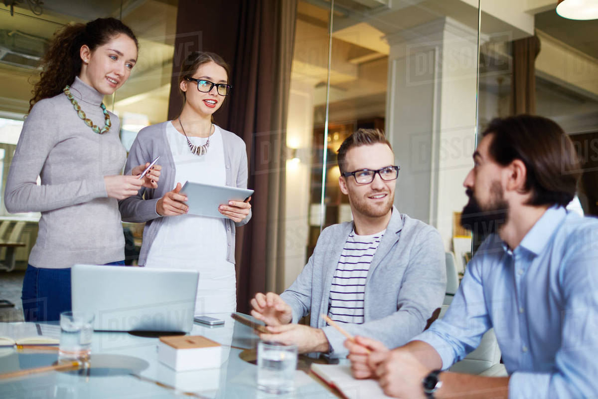 Young women looking at their colleagues and asking them questions ...