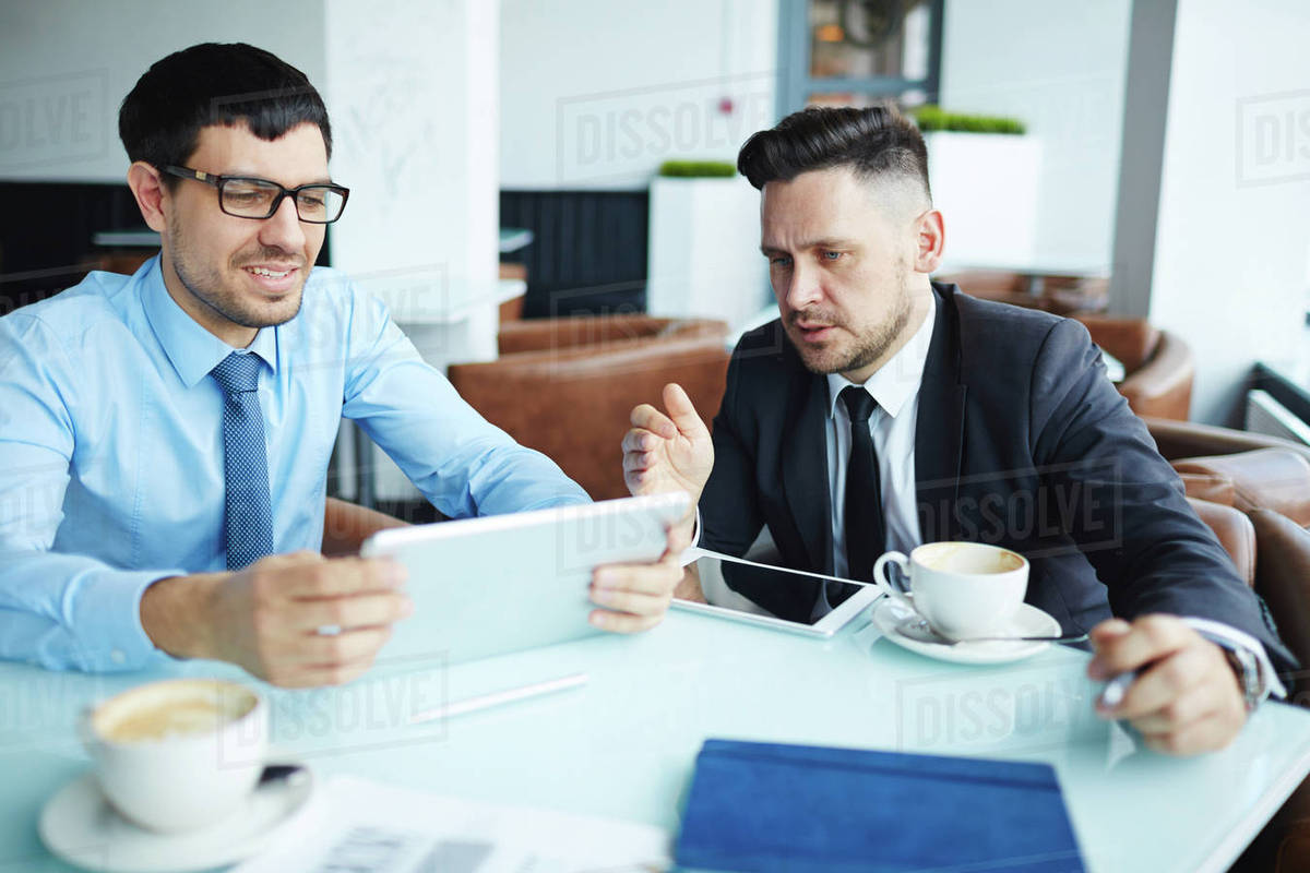 Two businessmen drinking coffee and working together at coffee shop ...