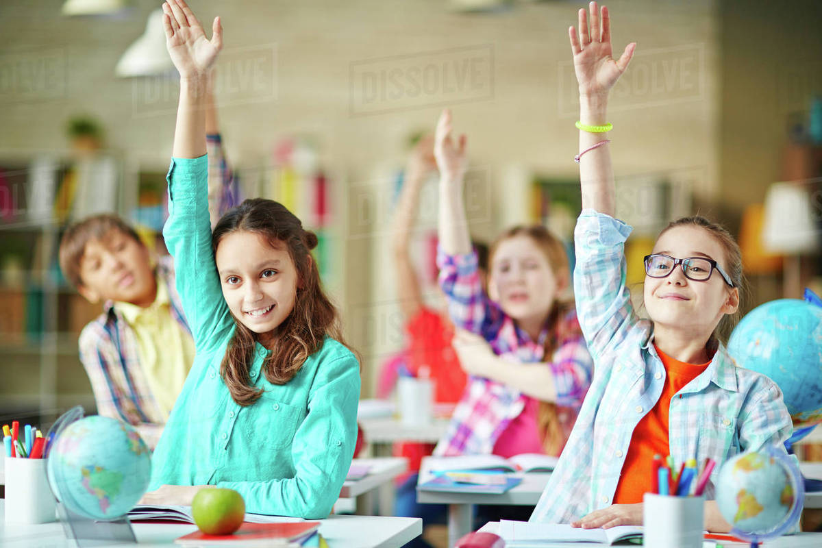 Intelligent group of school children raising their hands in to answer a ...