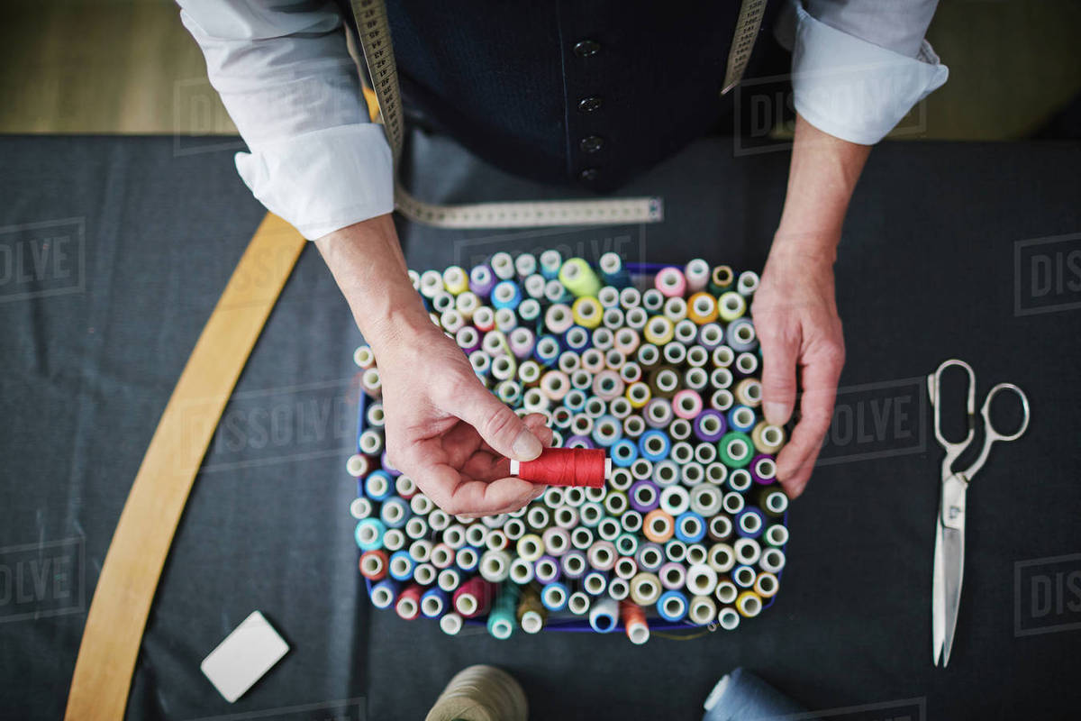 Tailor choosing suitable color of threads - Stock Photo - Dissolve
