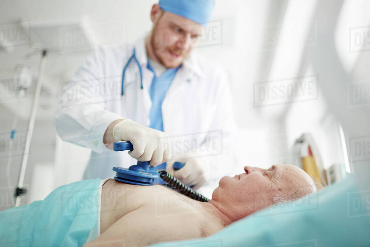 An elderly man lying unconscious and doctor reanimating him - Royalty ...