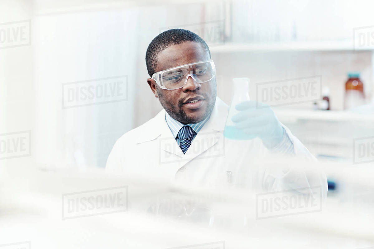 Young scientist looking at flask with blue liquid - Royalty-free Stock ...