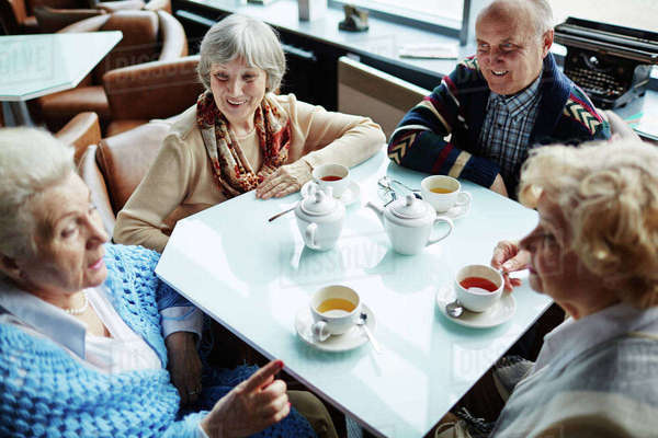 Group of friendly seniors talking by tea in cafe - Stock Photo - Dissolve