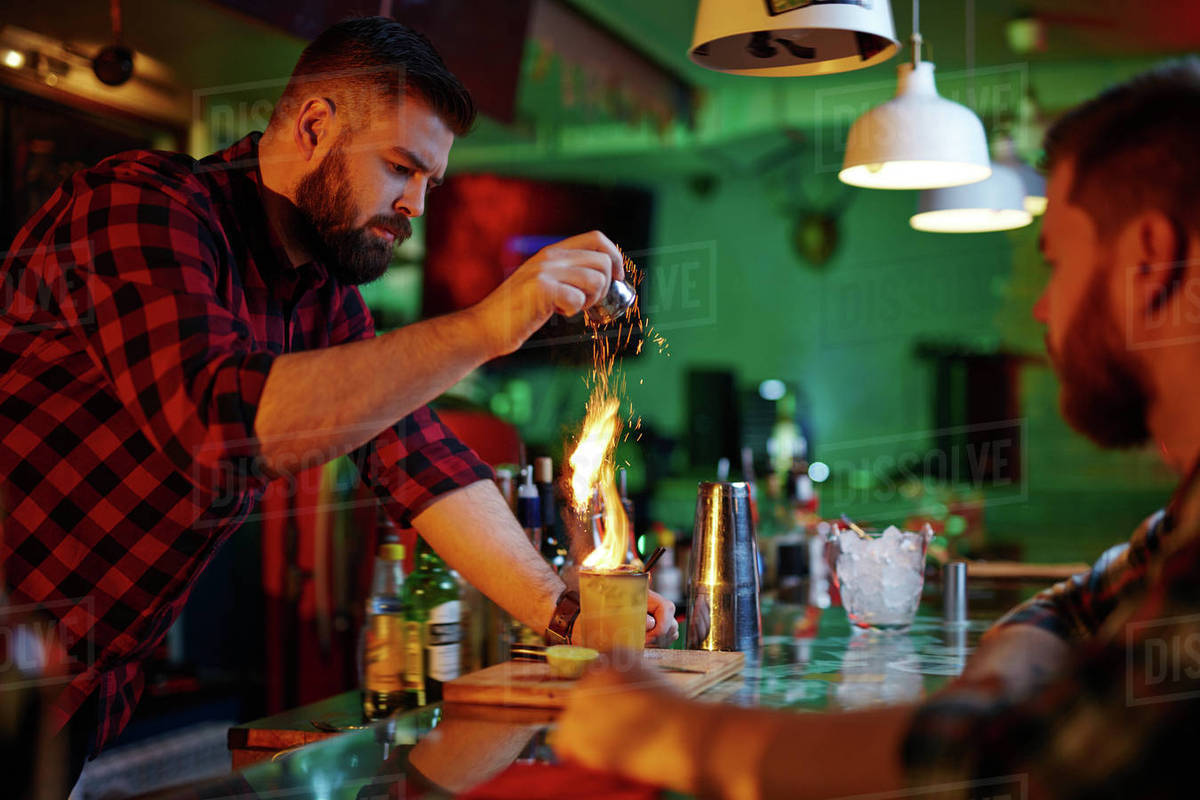 Young barman putting powder hot pepper into flaming cocktail - Stock ...