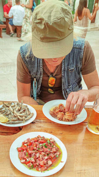 Man eating in a seafood restaurant that serves fish dishes with octopus ...
