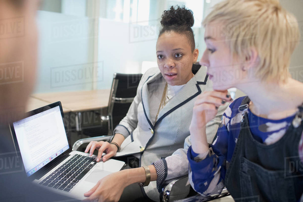 Group of young professionals collaborating in office with their laptops ...