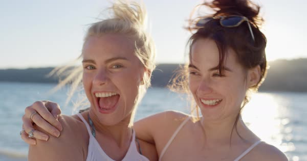 Beautiful young woman giving girl friend kiss on cheek hugging each ...