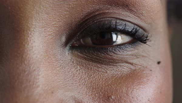 Close up of black woman eye looking at camera blinking pensive ...