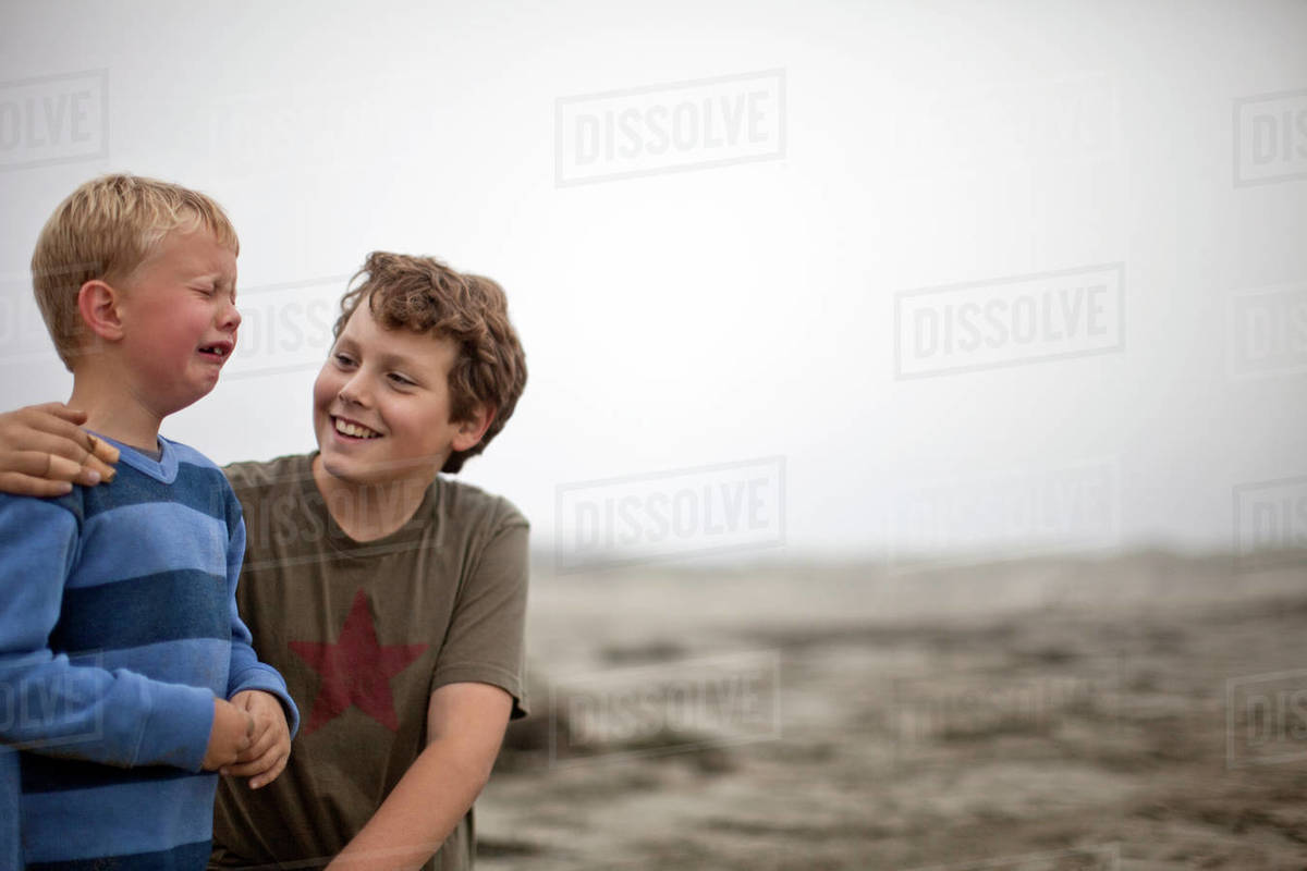 Boy comforting his crying younger brother on beach. - Stock Photo ...