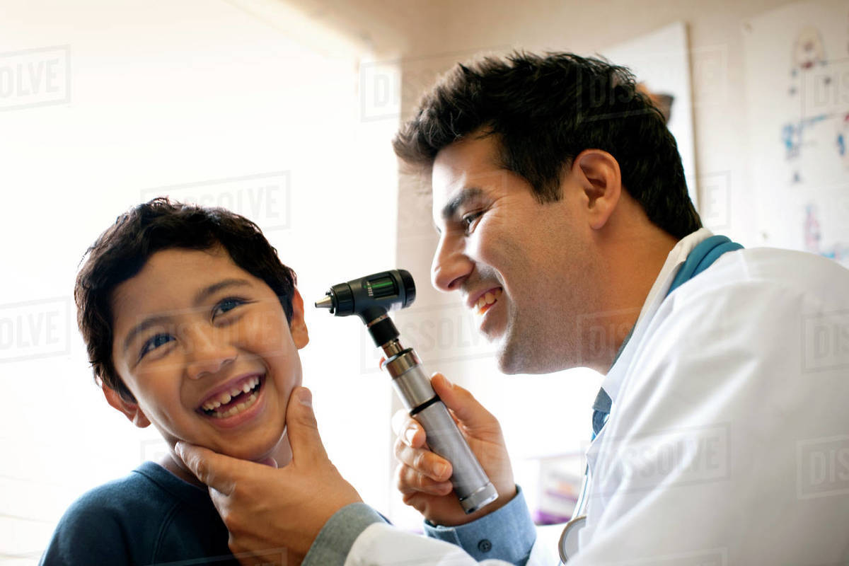 Doctor examining his young patient's ear with otoscope. - Royalty-free ...