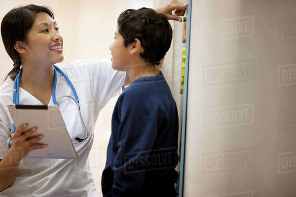 Nurse measuring a young boys height. - Royalty-free Stock Photo | Dissolve