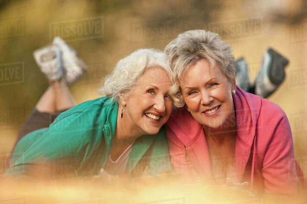 Portrait of two laughing senior women lying next to each other in a ...