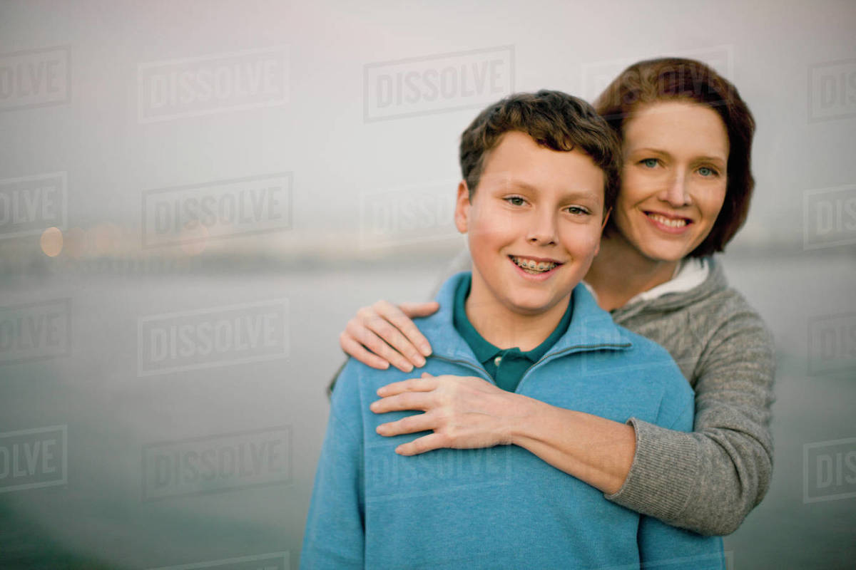 Mother happily standing with arm around her son. - Stock Photo - Dissolve
