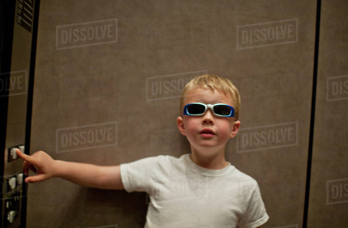Young boy pressing a button in an elevator. - Stock Photo - Dissolve