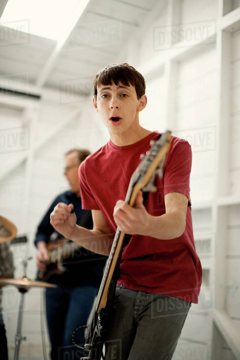 Teenage boy playing a bass guitar enthusiastically. - Royalty-free ...