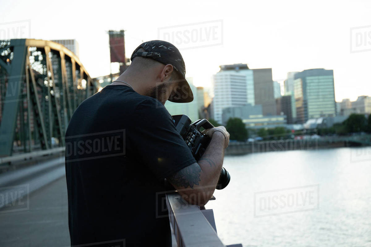 Man looking at digital camera while standing on bridge - Stock Photo ...