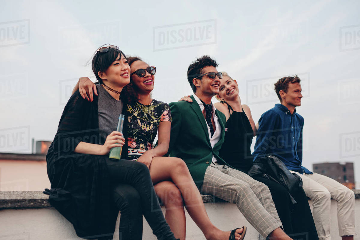 Shot of young friends hanging out together on rooftop. Multiracial ...