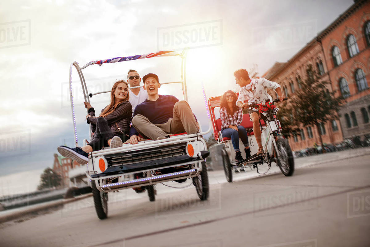 Happy young friends going on tricycle ride through the city. Teenagers ...
