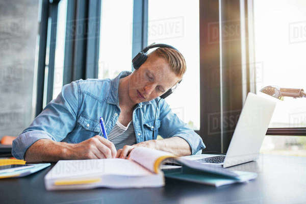 Shot of young man studying in college library sitting at table with ...