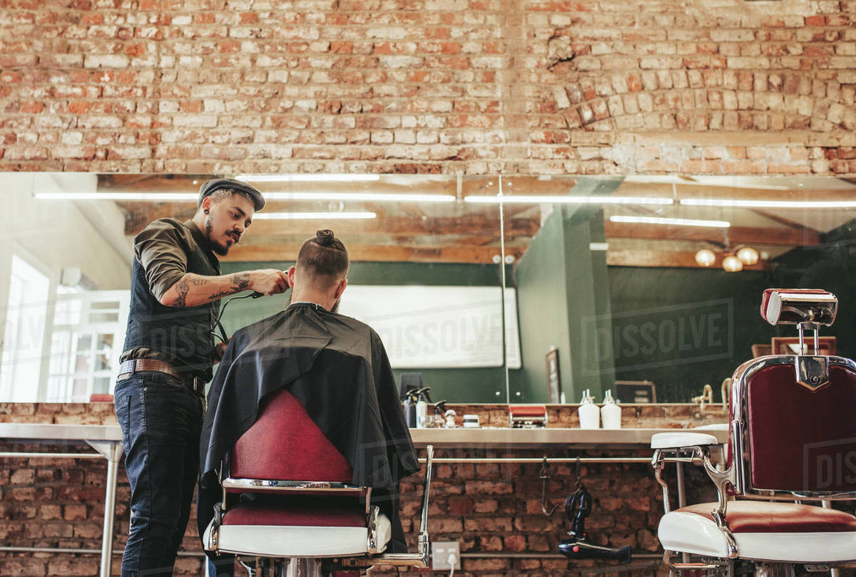 Stylish barber giving haircut to client at his shop. Hairdresser ...