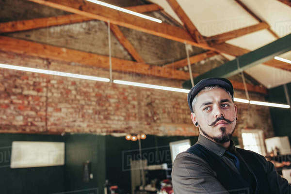 Close up shot of young man with cap standing in barber shop. Handsome ...