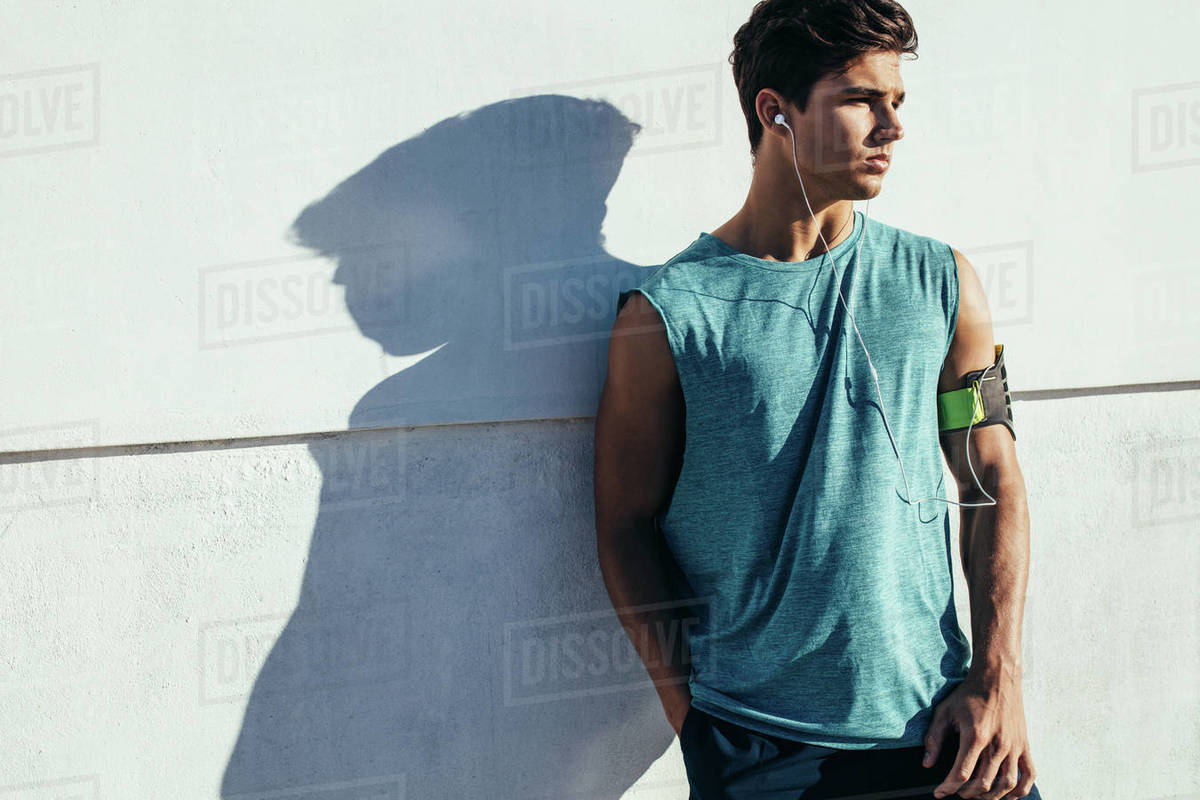 Outdoor shot of handsome young man relaxing after a run. Fitness male ...
