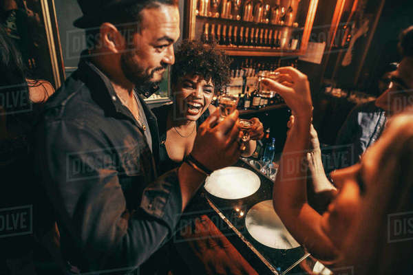 Happy young people having fun with drinks at nightclub. Man and women ...