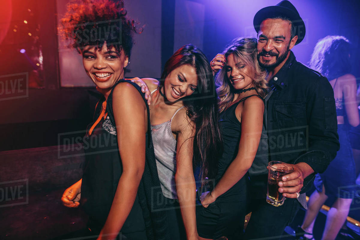 Young man and woman enjoying a party at nightclub. Group of friends ...