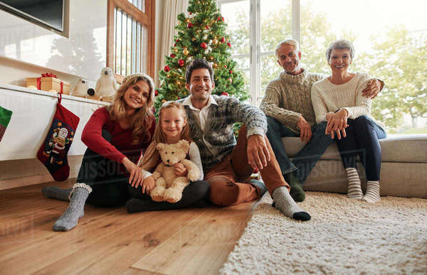 Portrait of a happy family sitting at home in the living room. Three ...