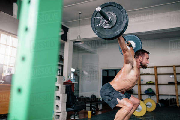 Powerful bodybuilder lifting barbell at the gym. Strong young man ...