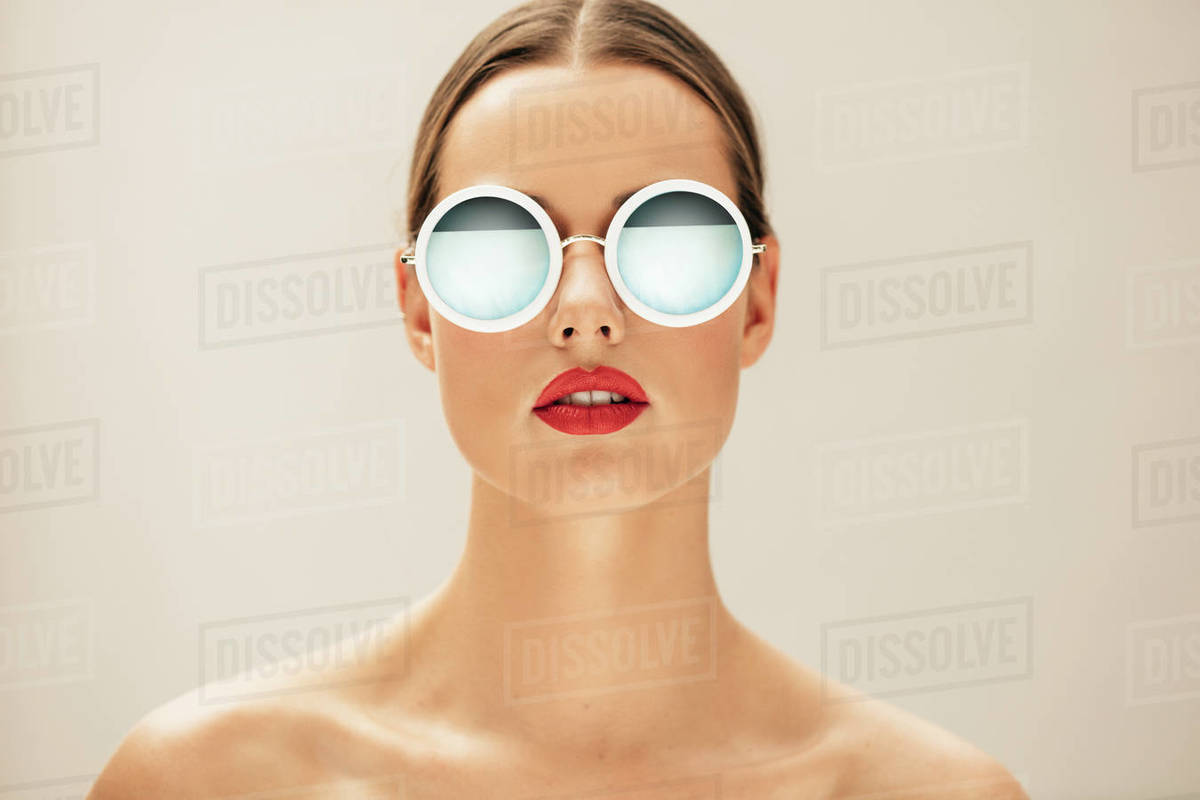 Close up portrait of pretty young woman with glasses against beige ...