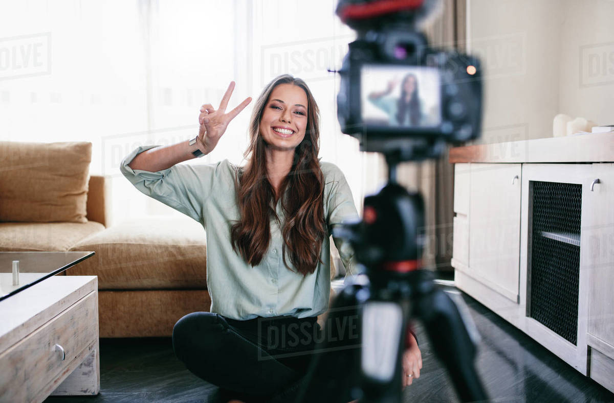 Young woman recording her daily video blog on a tripod mounted camera ...