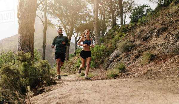 Young people trail running on a mountain path. Two runners working out ...