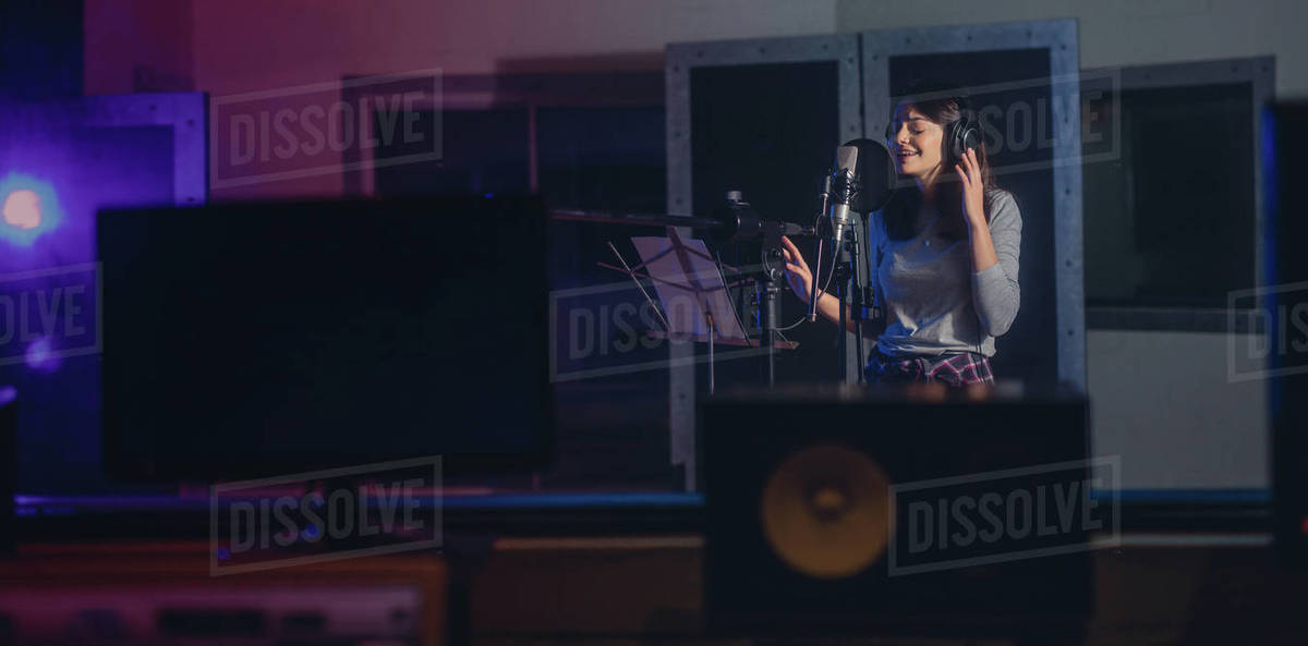 Woman recording a song in music studio. Female playback singer ...