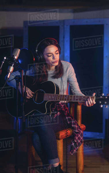 Female singer playing guitar and performing a song in studio. Woman ...