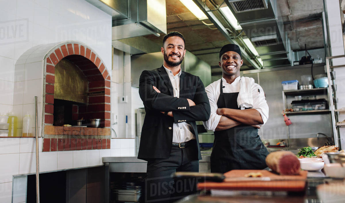 Portrait of restaurant manager with chef in kitchen. Businessman with ...