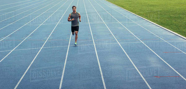 Athlete running on an all-weather running track alone. Runner sprinting ...