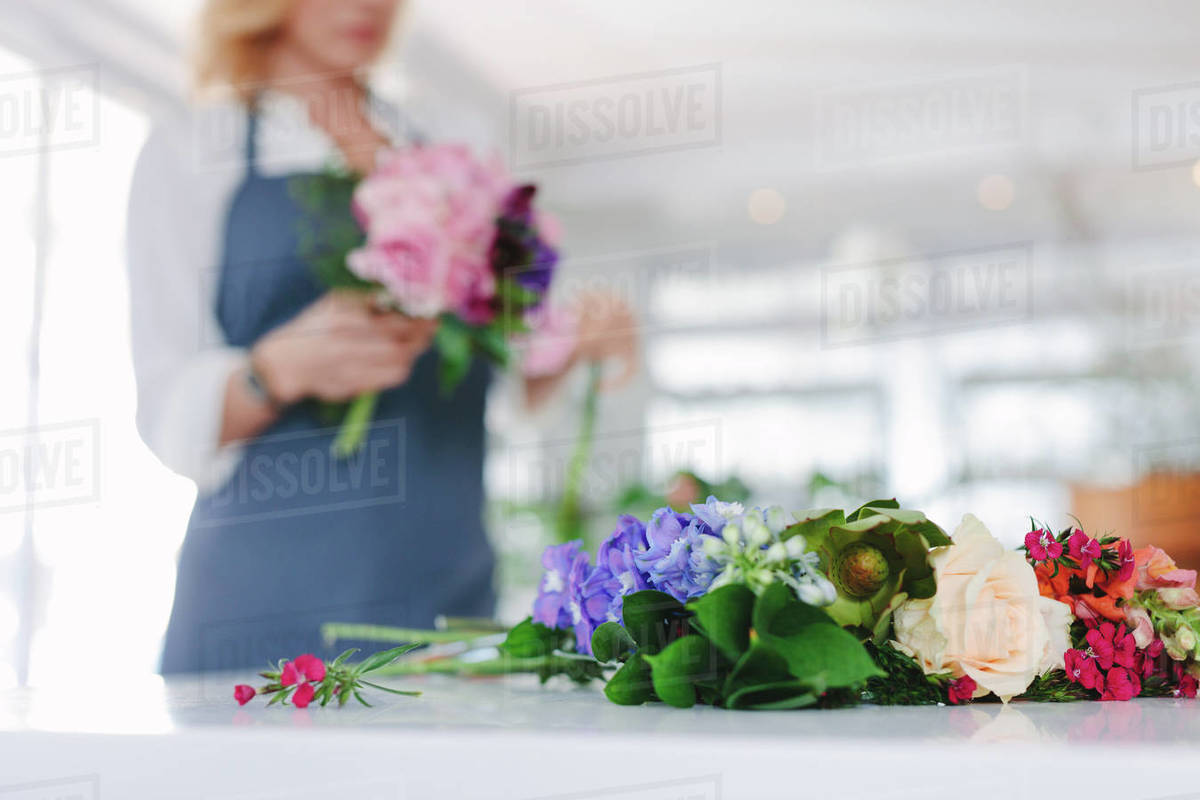 Fresh flower on counter with woman florist working in background. Focus ...