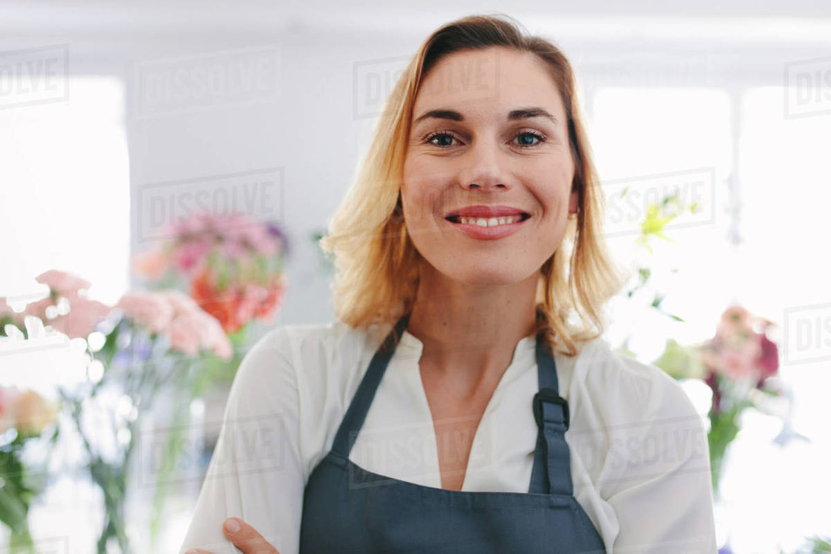 Close up of young successful florist standing in her own flower shop ...